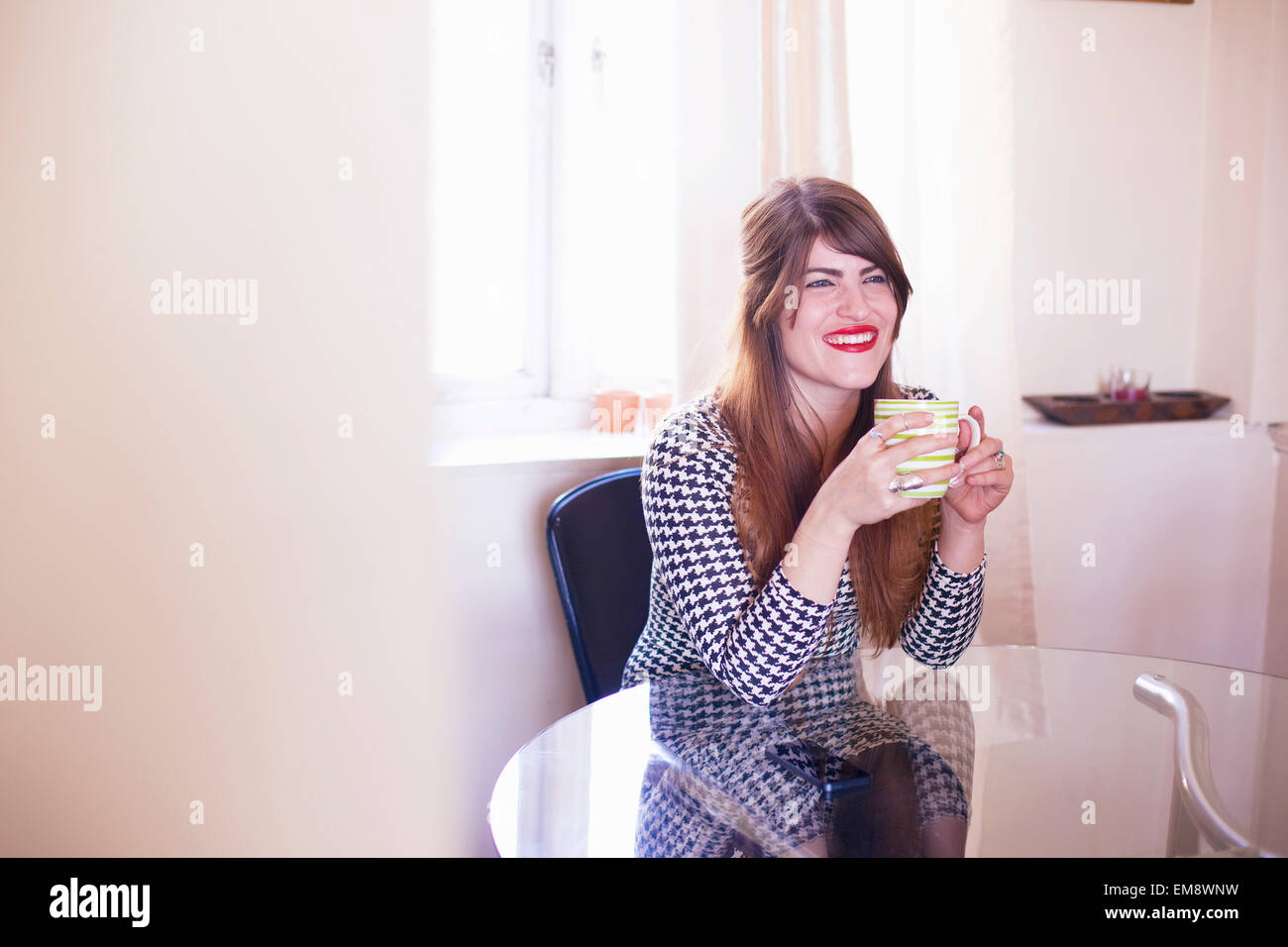 Woman sitting at table, drinking coffee Stock Photo - Alamy