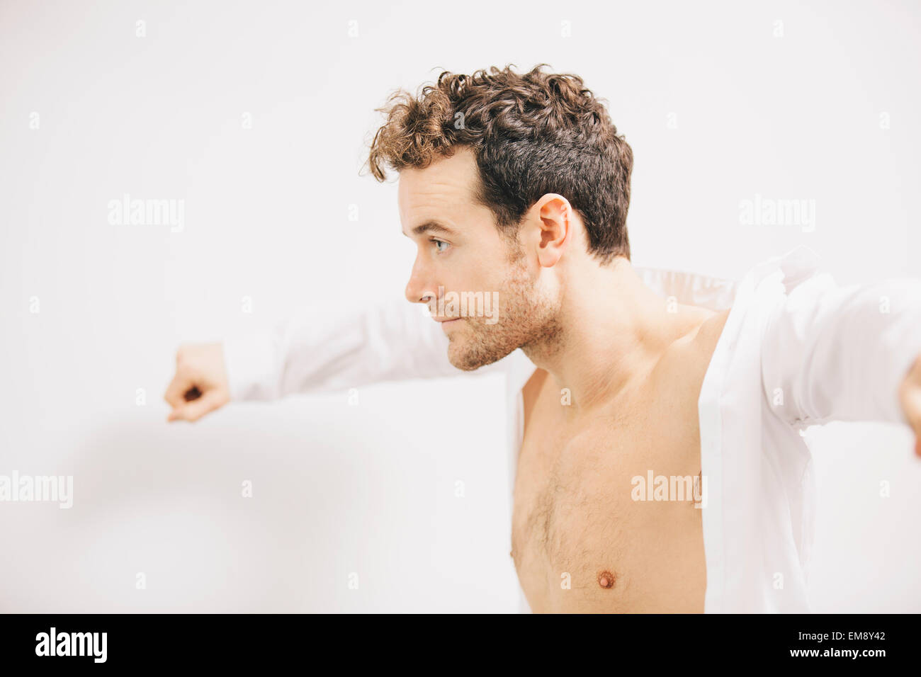 Young businessman putting on shirt in apartment Stock Photo - Alamy