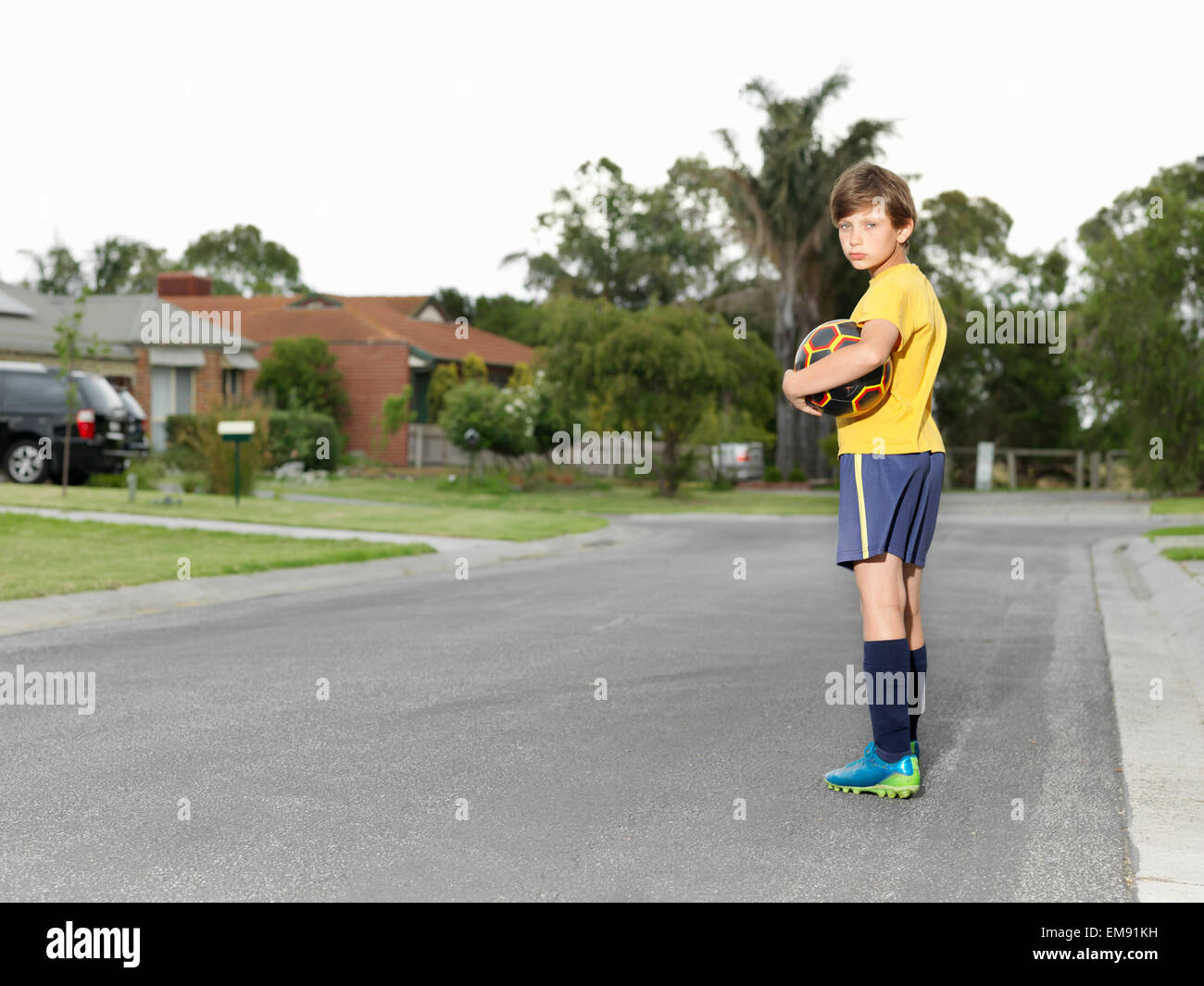 Boy holding football on roadside hi-res stock photography and images ...