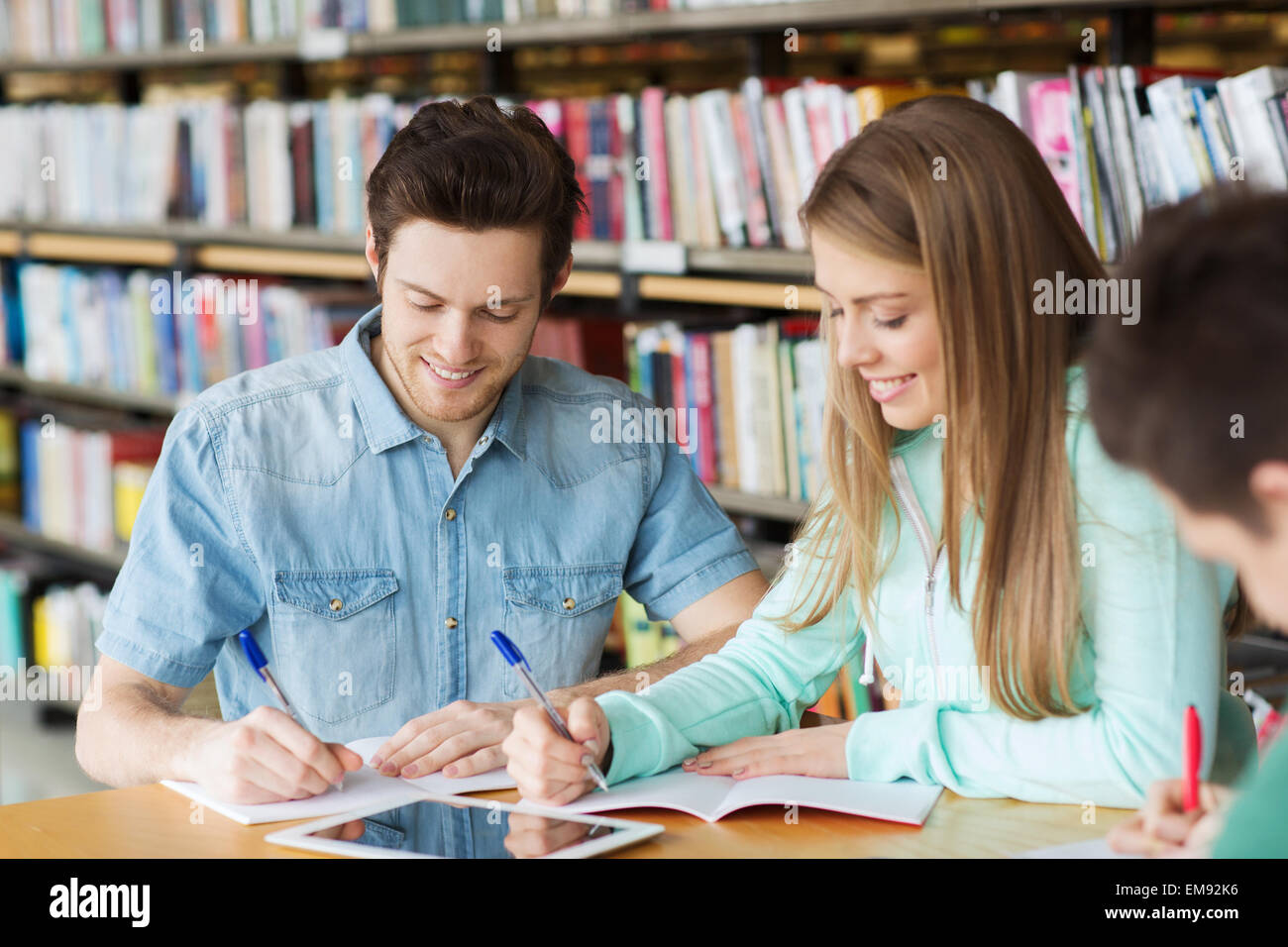 happy students writing to notebooks in library Stock Photo - Alamy