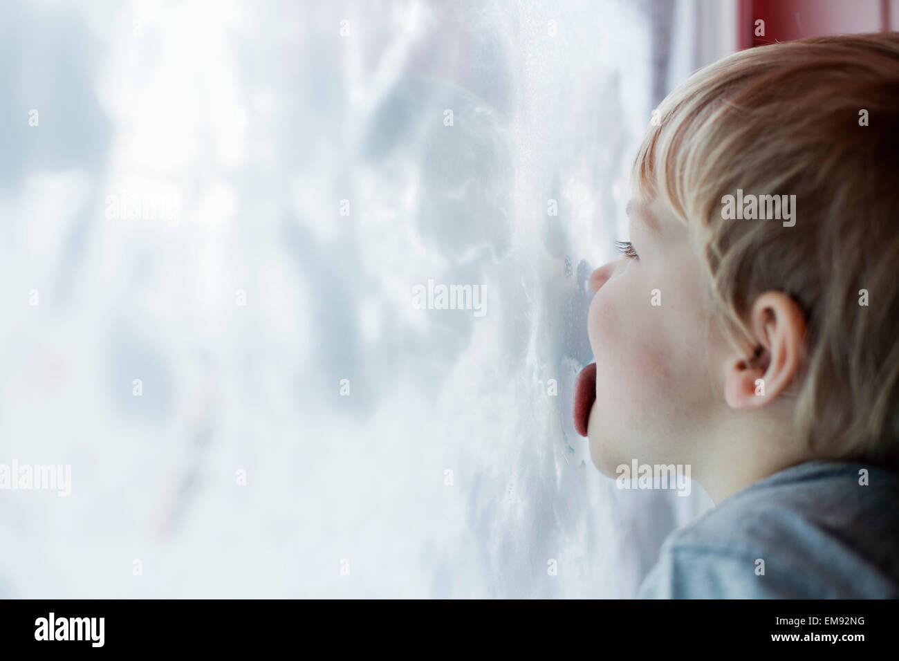 Boy licking inside of snow-covered window Stock Photo - Alamy