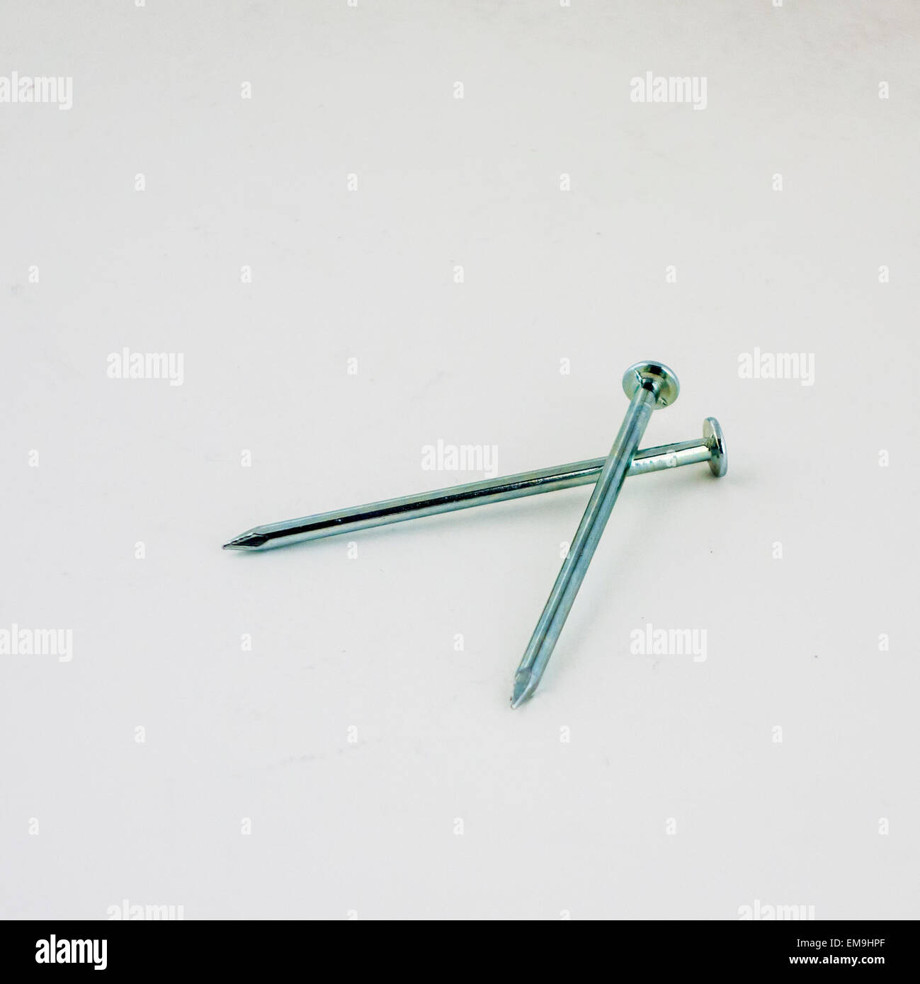 Two nails, one lying upon the other, isolated on white. Conceptial ...