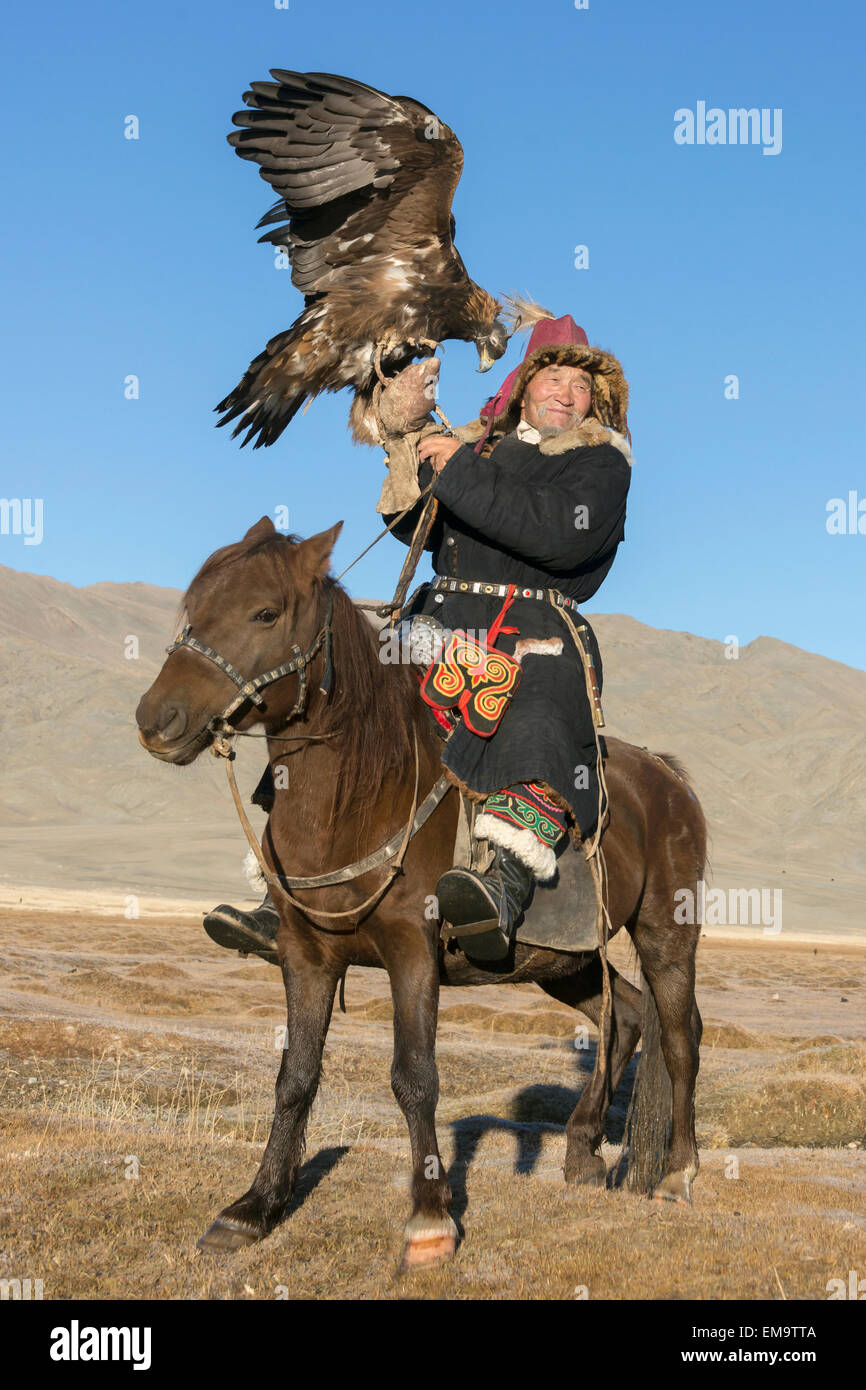 Elder Kazakh eagle hunter posing with his eagle and his horse #2 ...