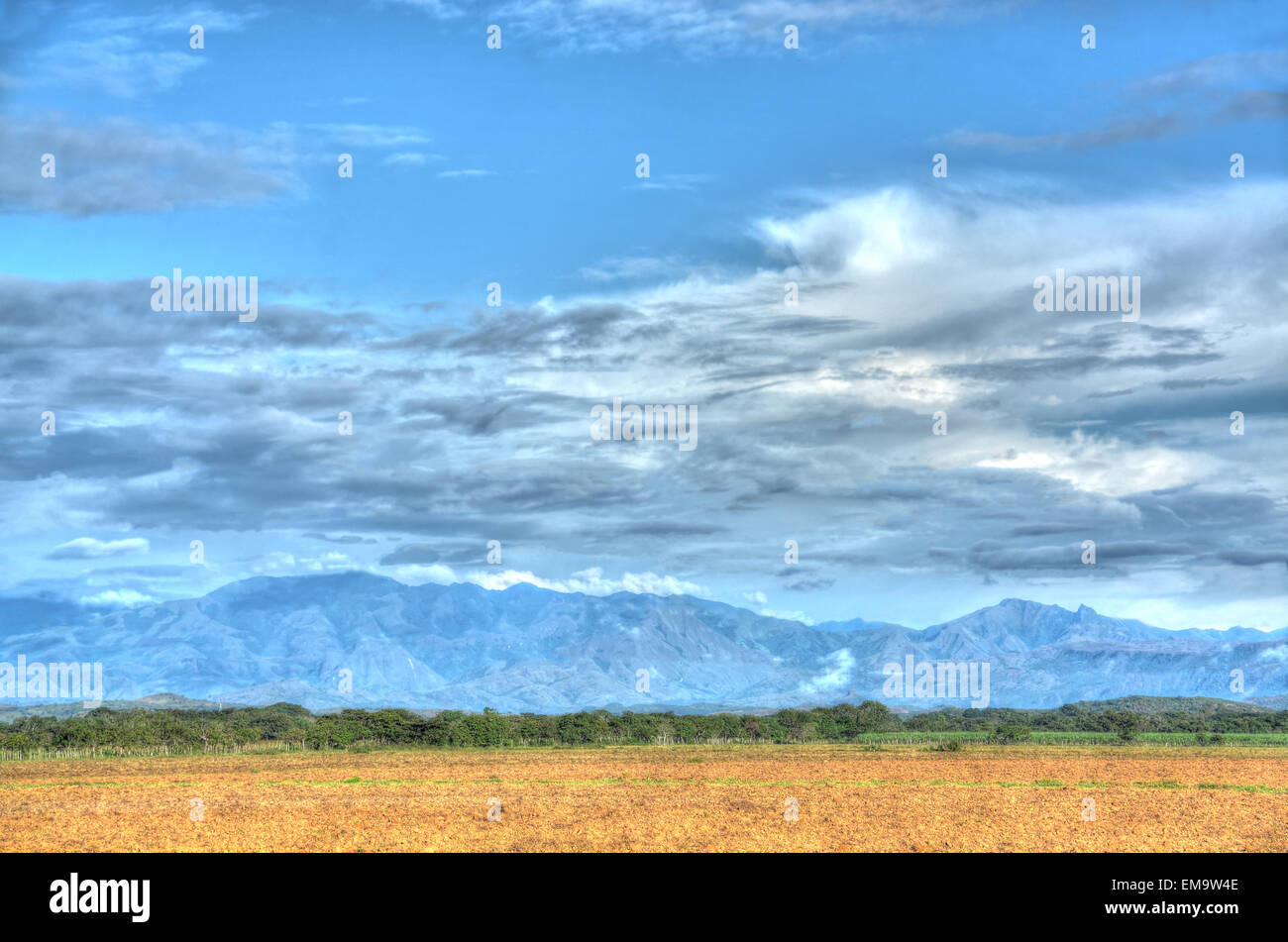 Plowed field with a beautiful blue sky and mountains in the background ...