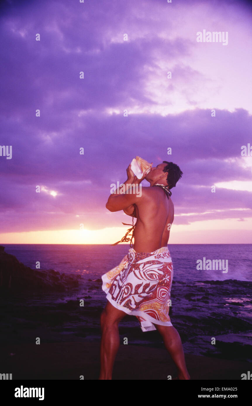 Hawaiian Man Blows Conch Shell At Beach, Sunrise With Purple And Yellow ...