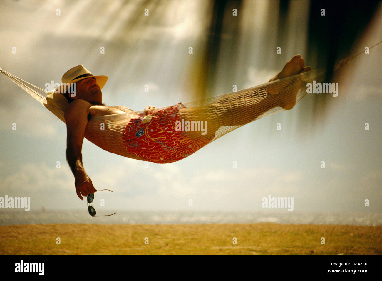 Man With Hat Resting In Hammock At Sunset, Sunglasses In Hand, Palm ...