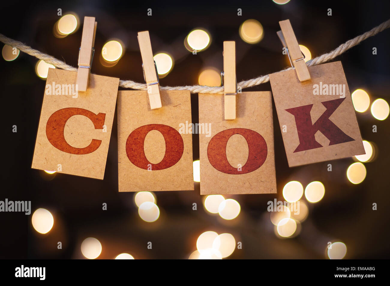 The word COOK printed on clothespin clipped cards in front of defocused ...