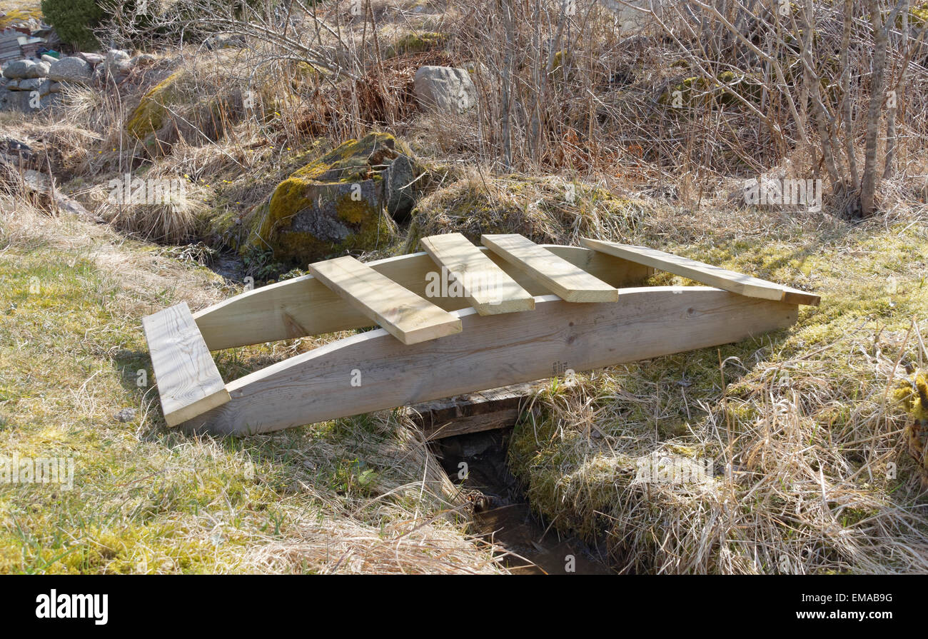 Building a small wooden curved bridge over the trench built of ...