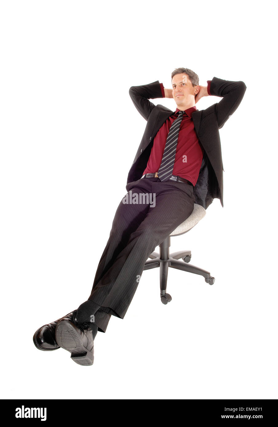 An business man in a suit sitting in a office chair, leaning back with ...