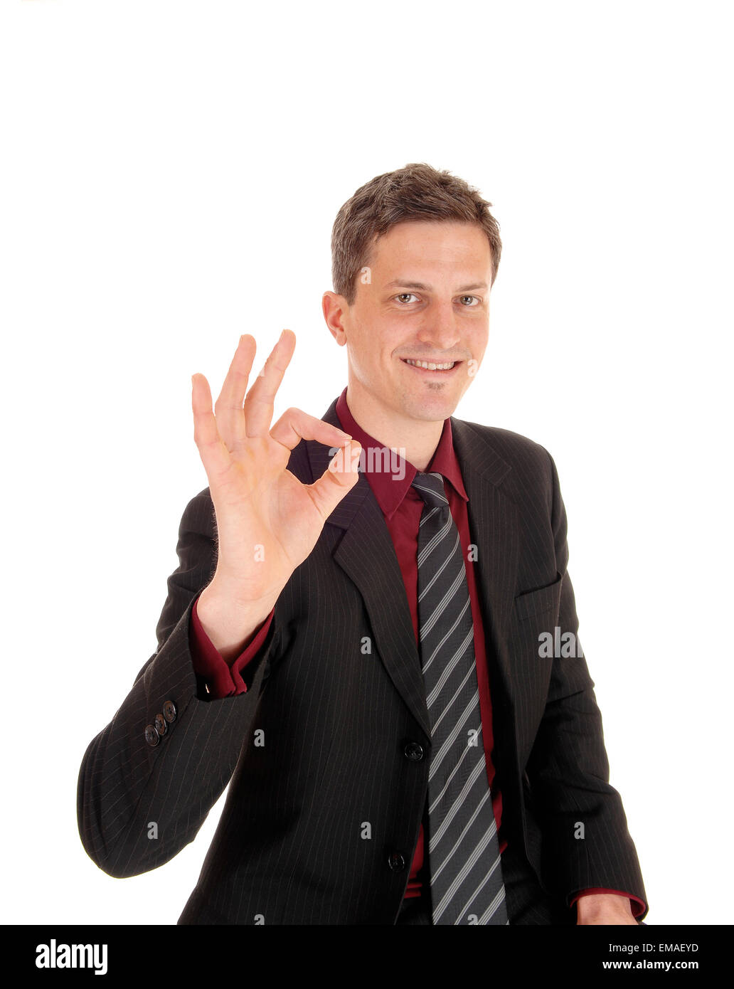 A business man standing in a suit and tie making an OK sign and smiling ...
