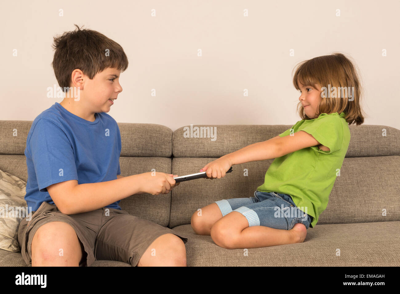 Kids arguing for playing with a digital tablet on a sofa Stock Photo ...