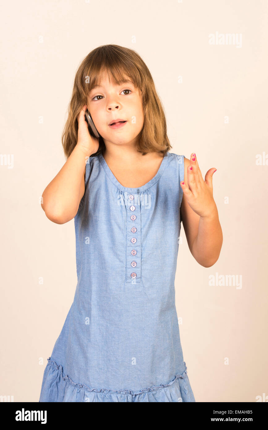 Little girl standing talking on cellphone with white background Stock ...