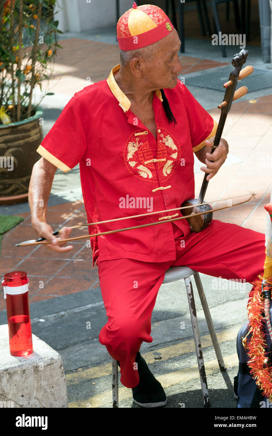 Chinese man in traditional costume playing an Erhu musical instrument ...