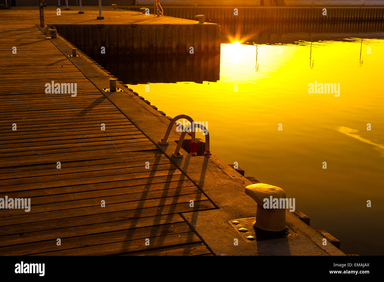 Wooden platform with a swimming pool ladder and calm, water in early ...