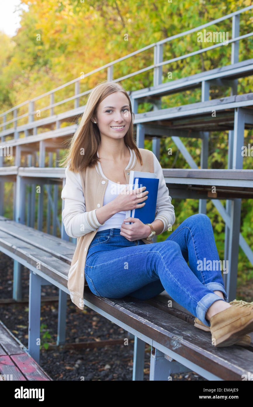 Student sitting on sport tribune and smiling at camera on the sunset ...