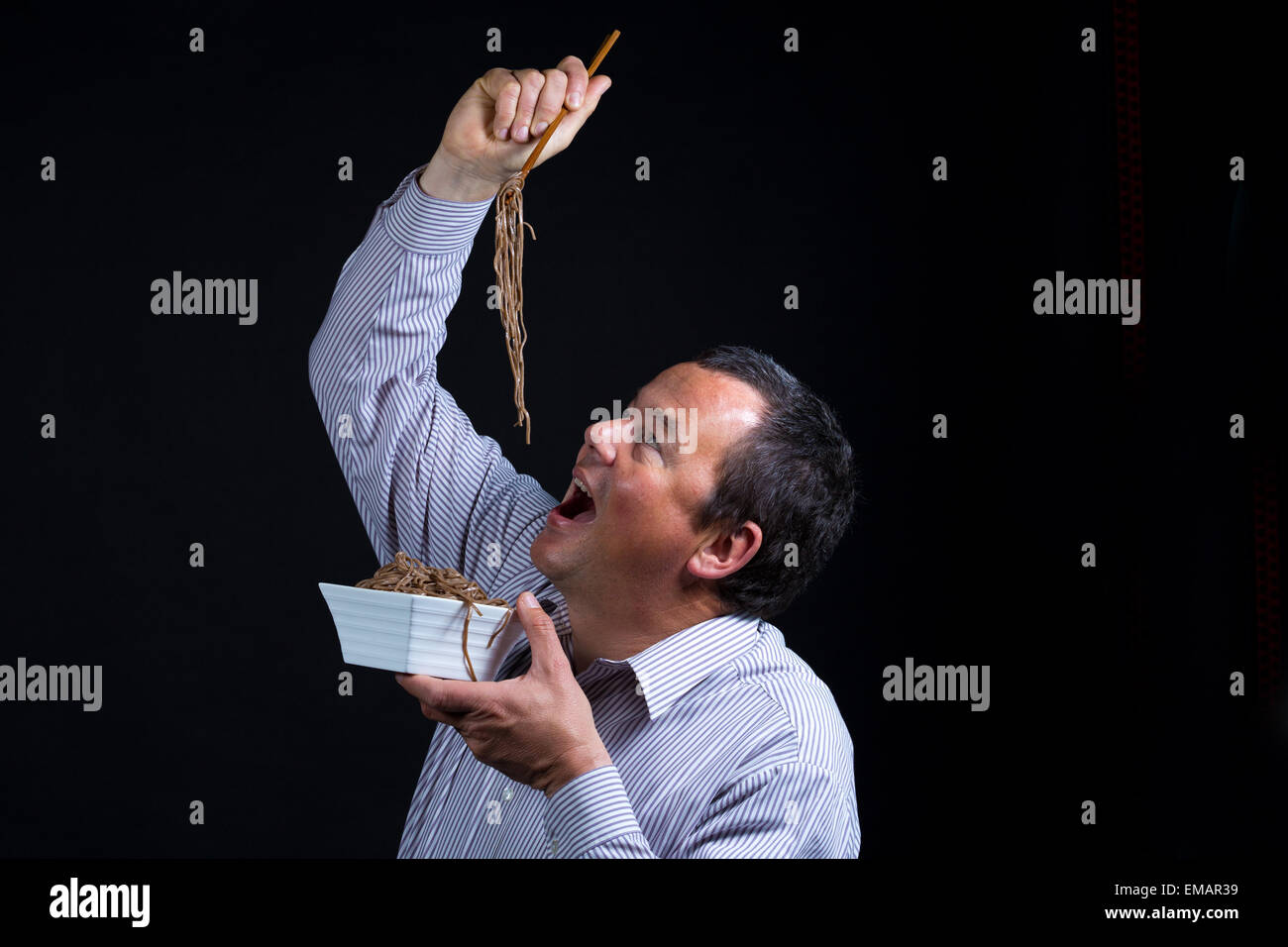 Eating with chopsticks, quite a challenge for this guy Stock Photo - Alamy