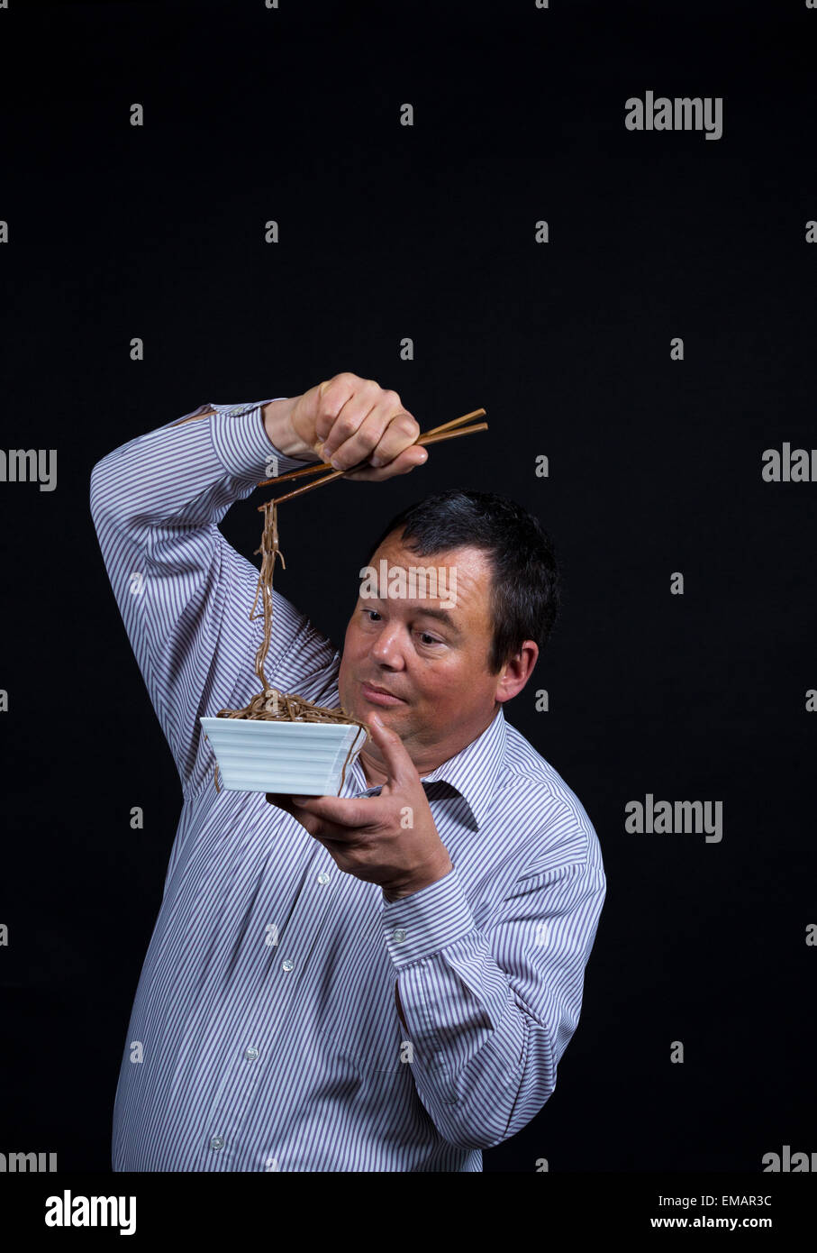Eating with chopsticks, quite a challenge for this guy Stock Photo - Alamy