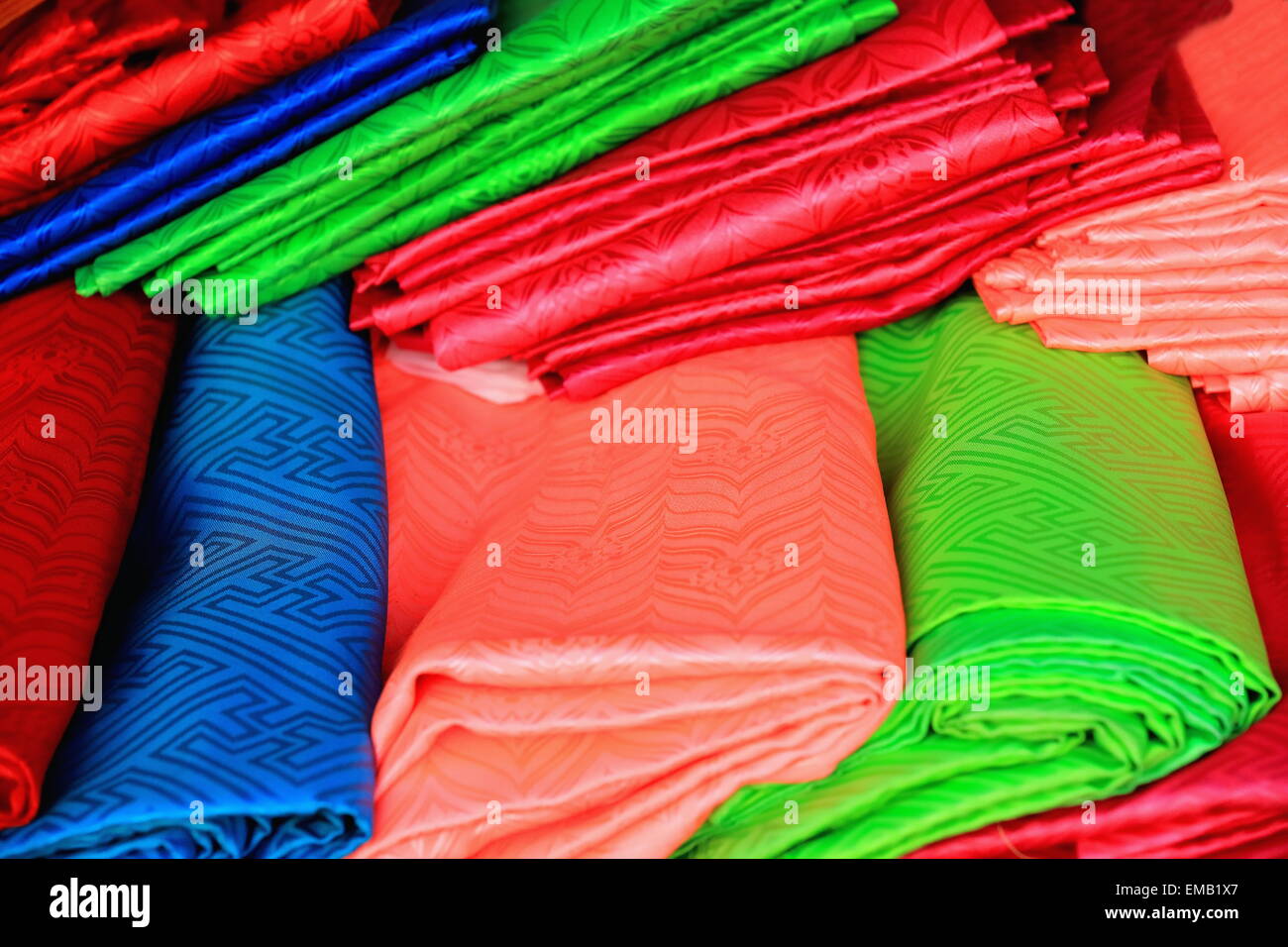 Colorist silk fabric pieces showing tibetan designs piled in a shop ...