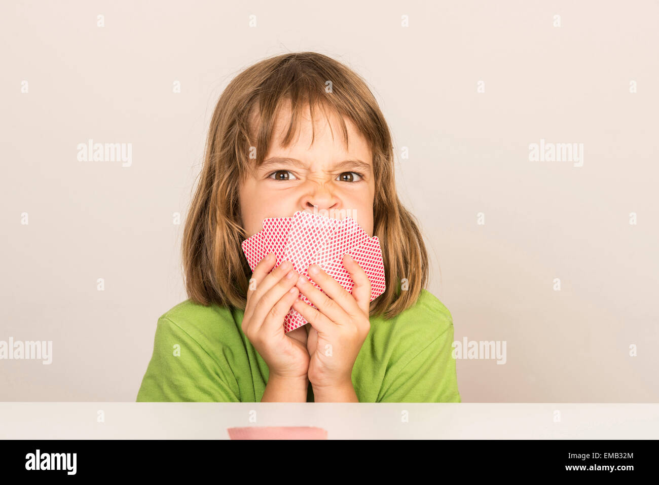 portrait of little girl playing cards with angry face Stock Photo - Alamy