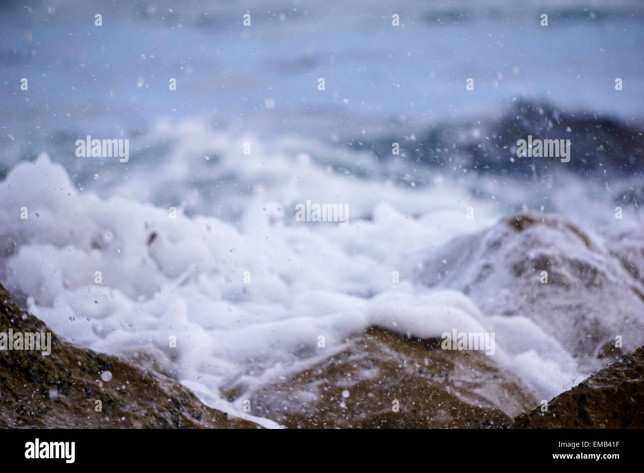 Waves crashing over rocks with ocean spray Stock Photo - Alamy