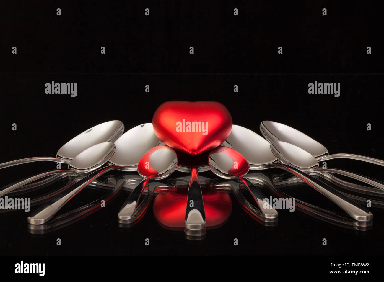 Nine spoons and red heart on a black glass desk Stock Photo - Alamy