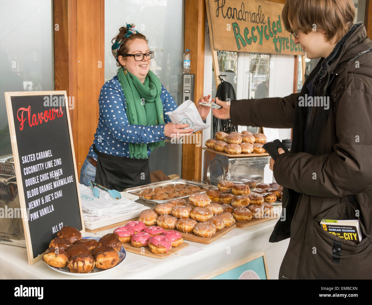 A lady selling doughnuts to a man at a market in Bristol, England Stock ...