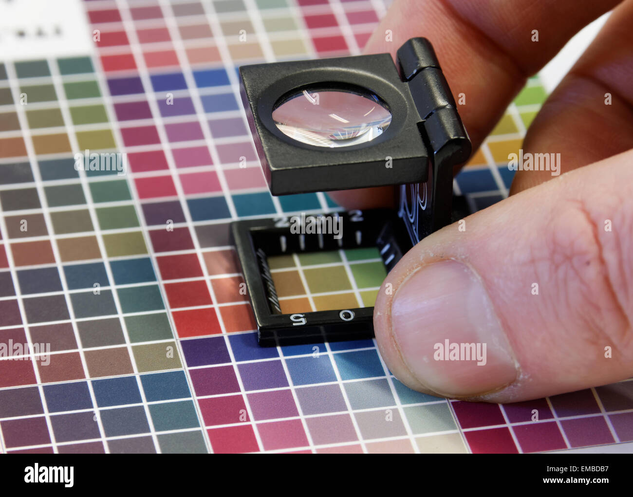 Close-up of a loupe on colorful, blurry inkjet test print with color ...