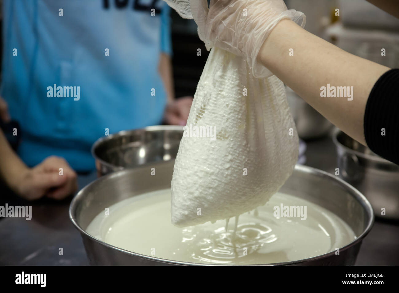 Women draining the feta cheese curds during a cheesemaking class in ...