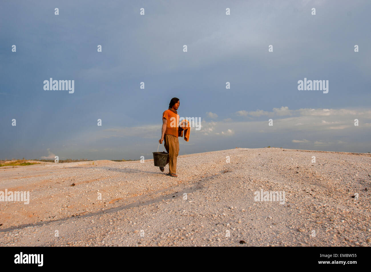 A small scale gold miner walking on moonscape-like landscape in ...