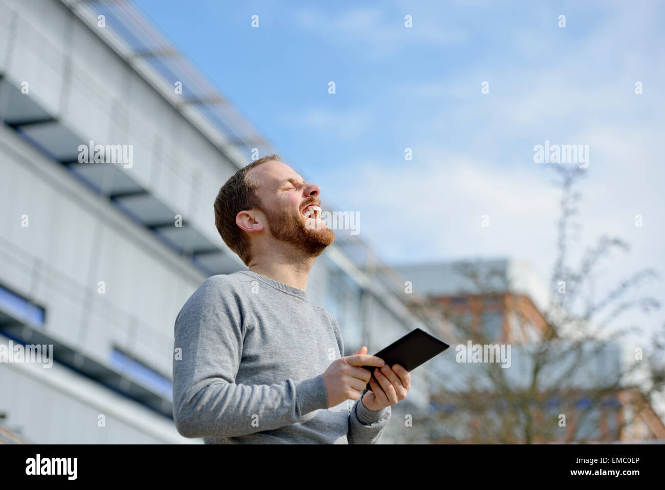 Portrait of laughing young man with mini tablet Stock Photo - Alamy