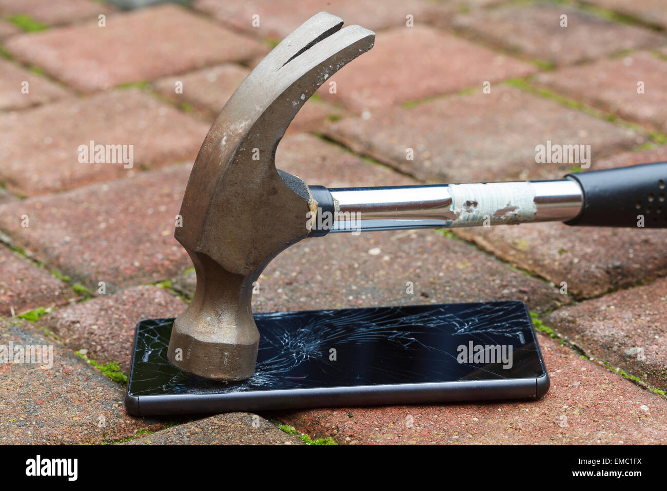 Broken mobile phone hit by hammer, lying on the pavement Stock Photo ...