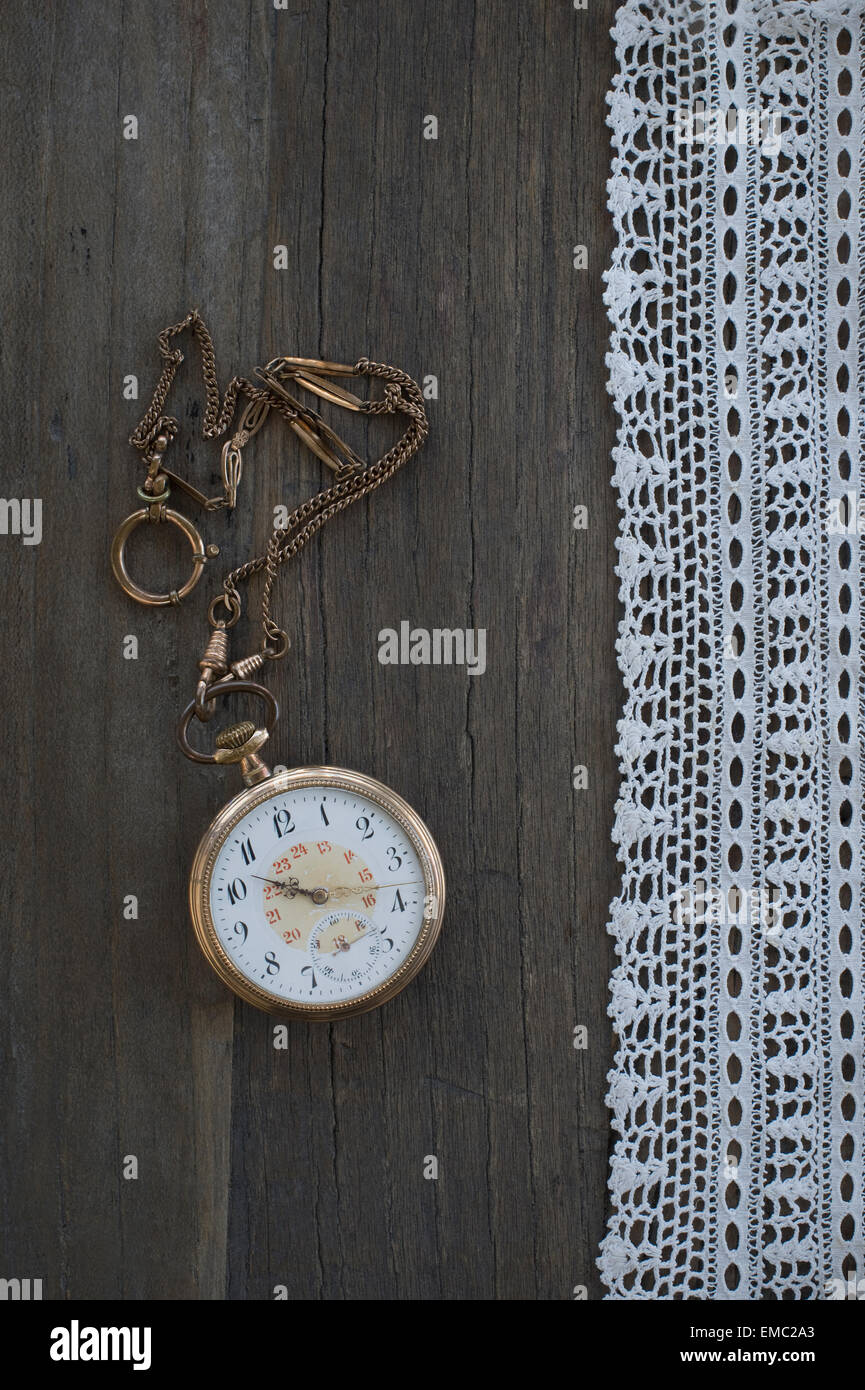 Old pocket watch and lace on dark wood Stock Photo - Alamy