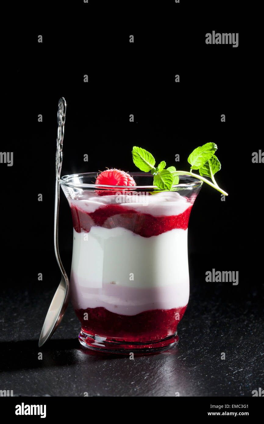 Glass of garnished raspberry junket in front of black background Stock ...