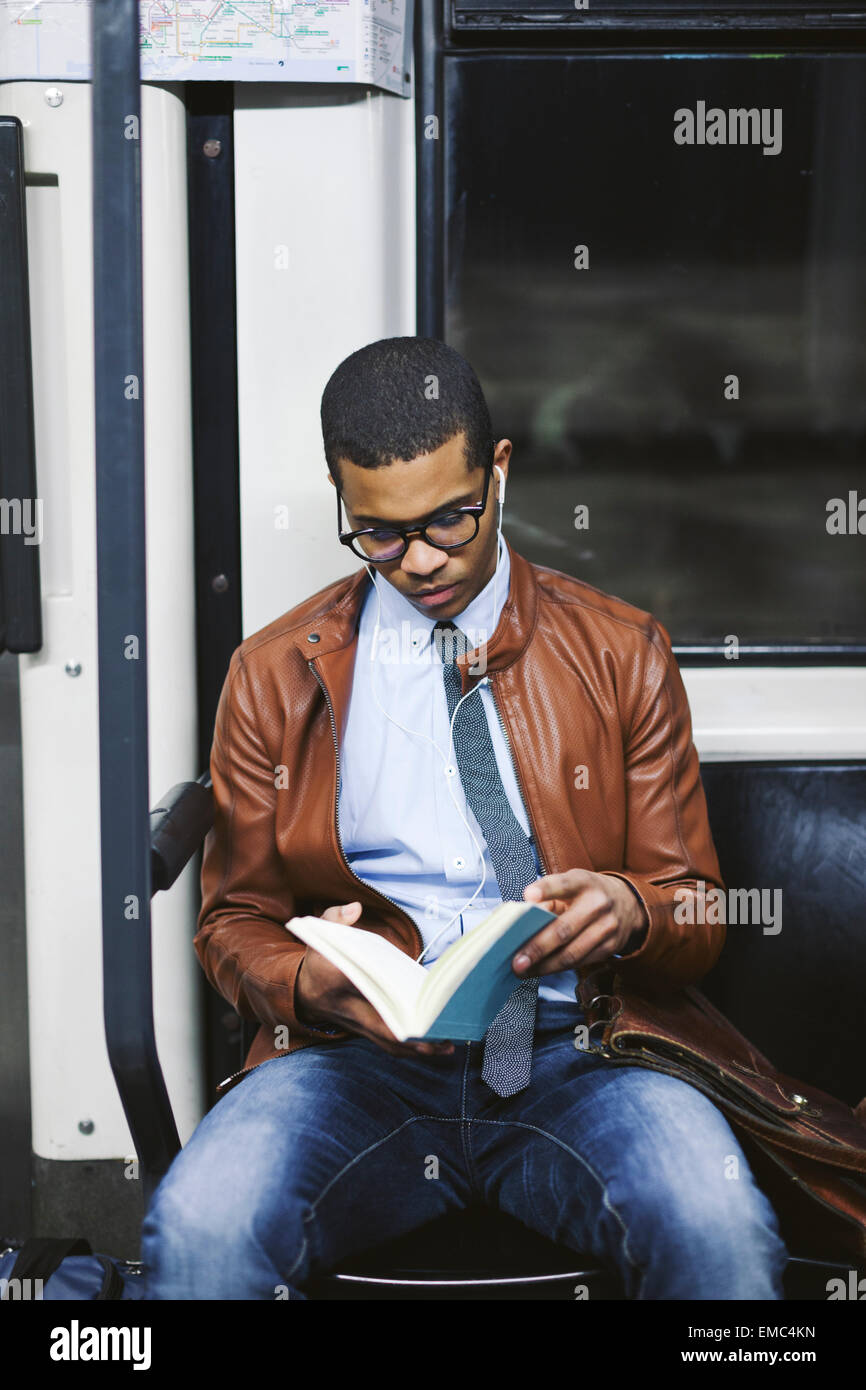 Businessman reading book on the subway train Stock Photo - Alamy