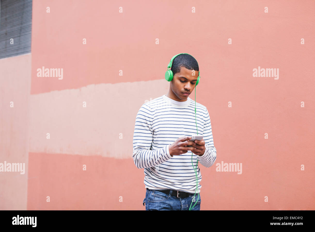 Young man hearing music with green headphones Stock Photo - Alamy