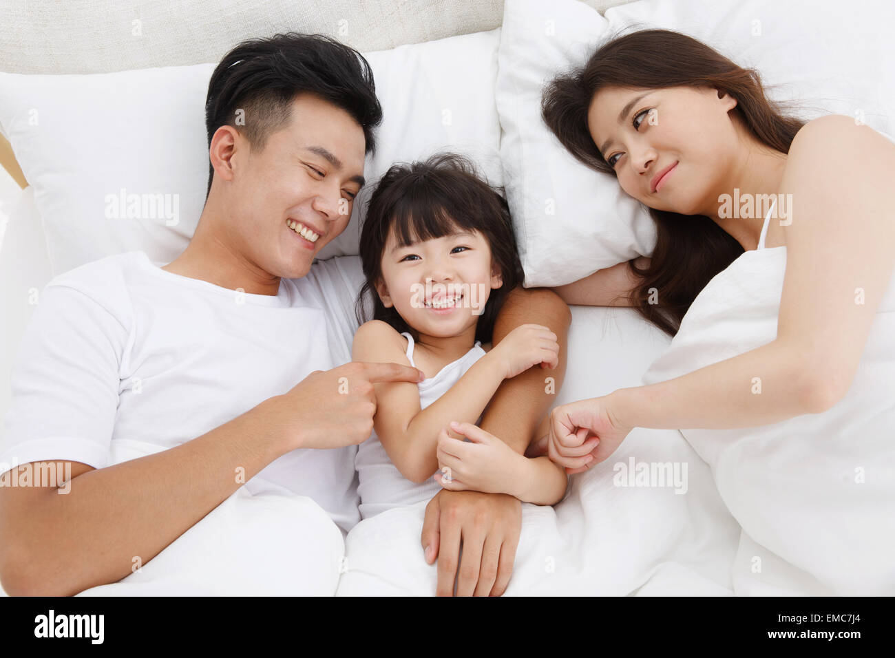 A family of three in the bedroom bed play Stock Photo - Alamy
