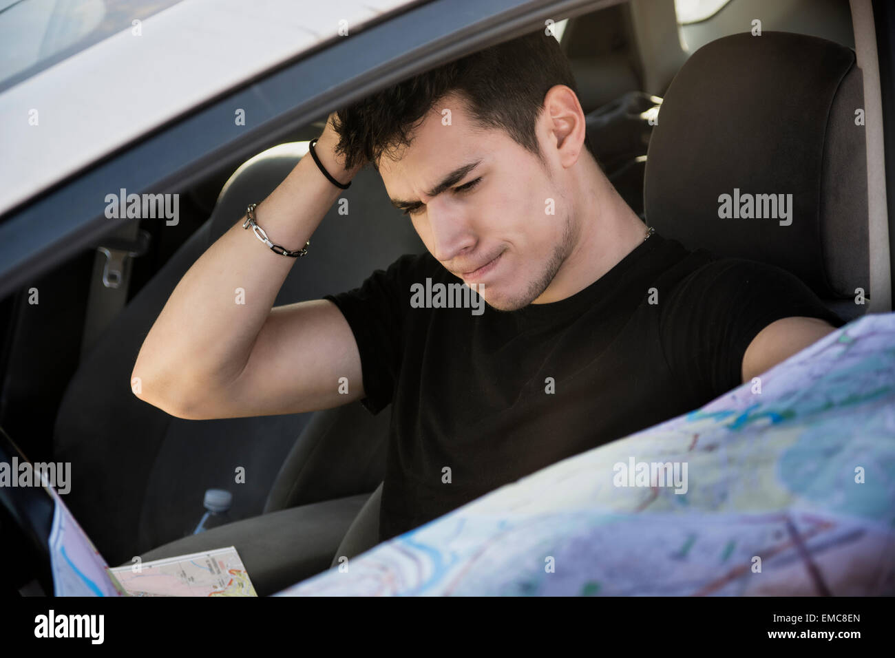Young Man Driving the Car, Holding a Map Confused and Puzzled Stock ...