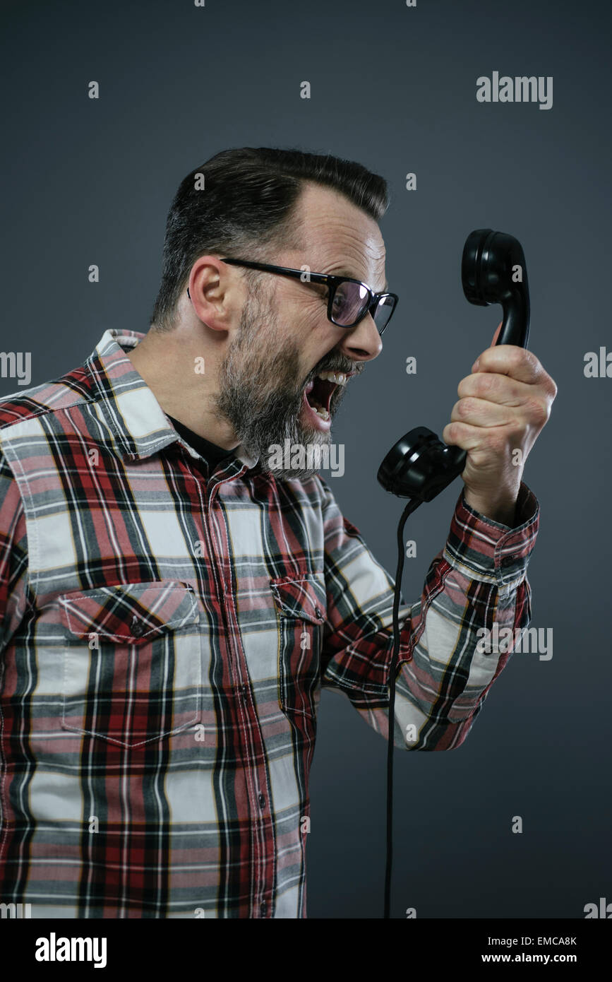 Man screaming into retro telephone in front of grey background Stock ...