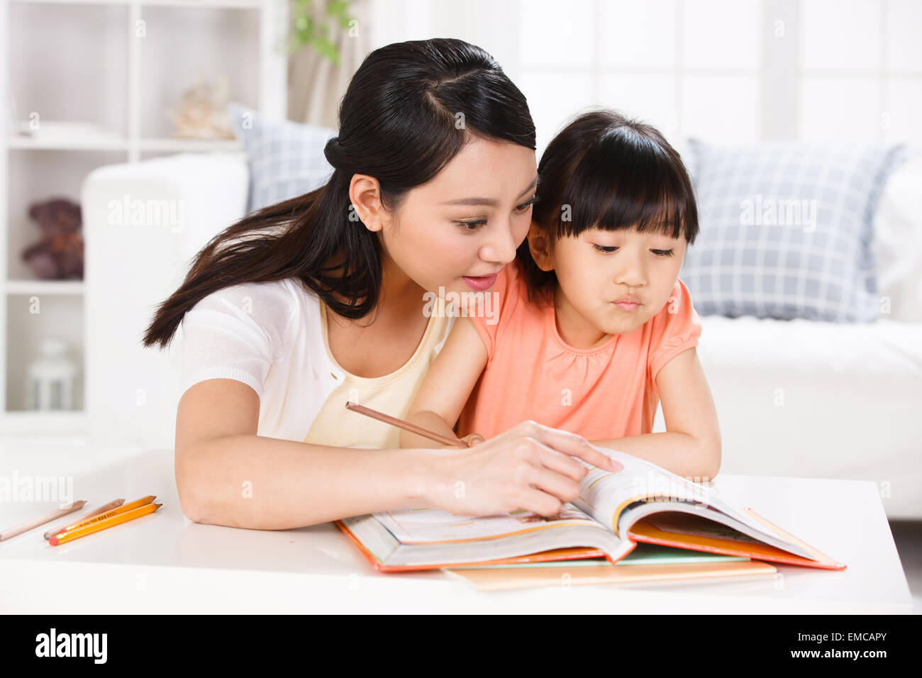 Mother guiding daughter study in the living room Stock Photo - Alamy