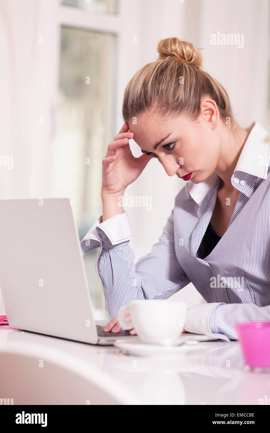 Unhappy blond woman sitting in a coffee shop using laptop Stock Photo ...