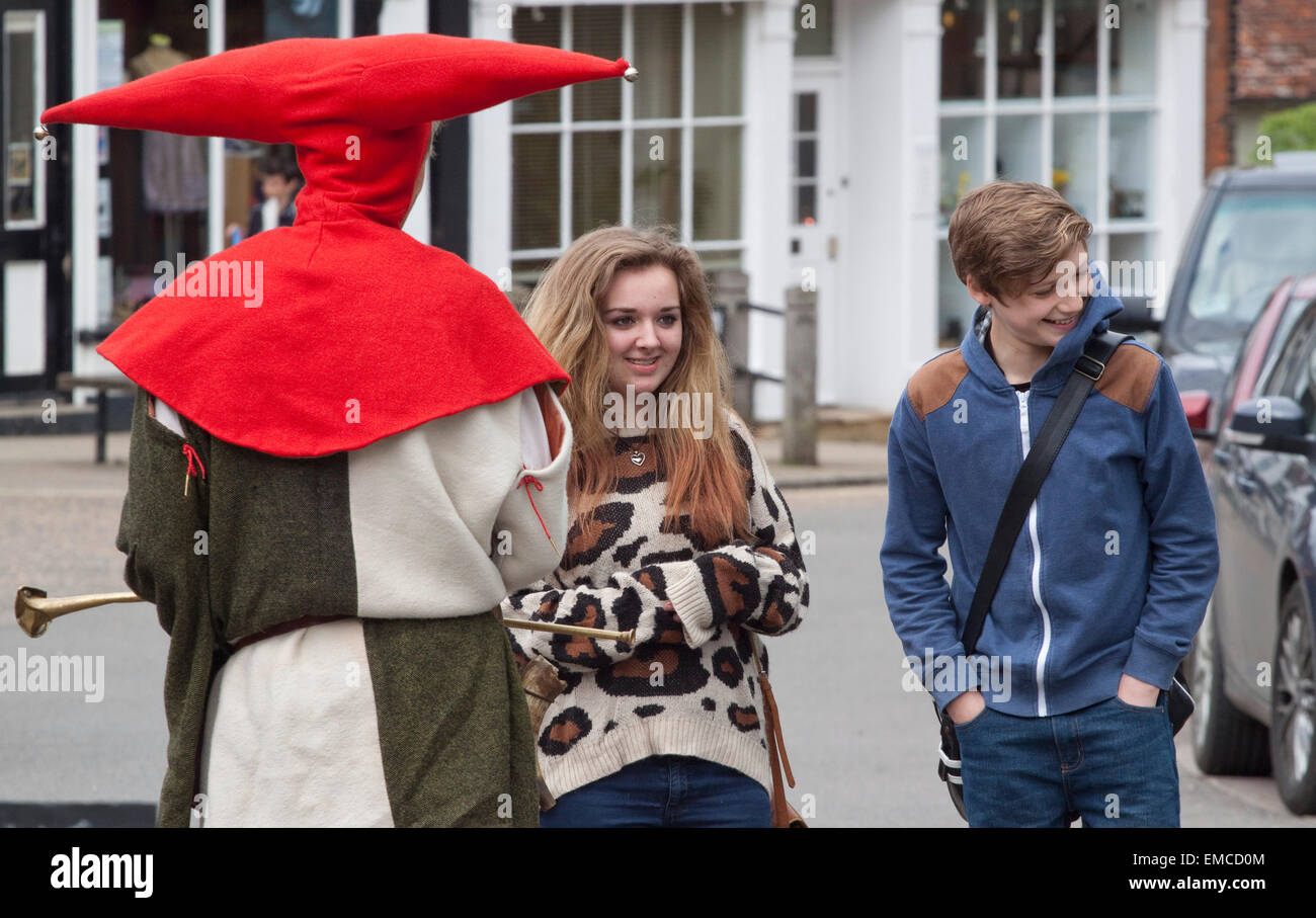 Jester in a ridiculous red costume makes two teenagers smile Stock ...