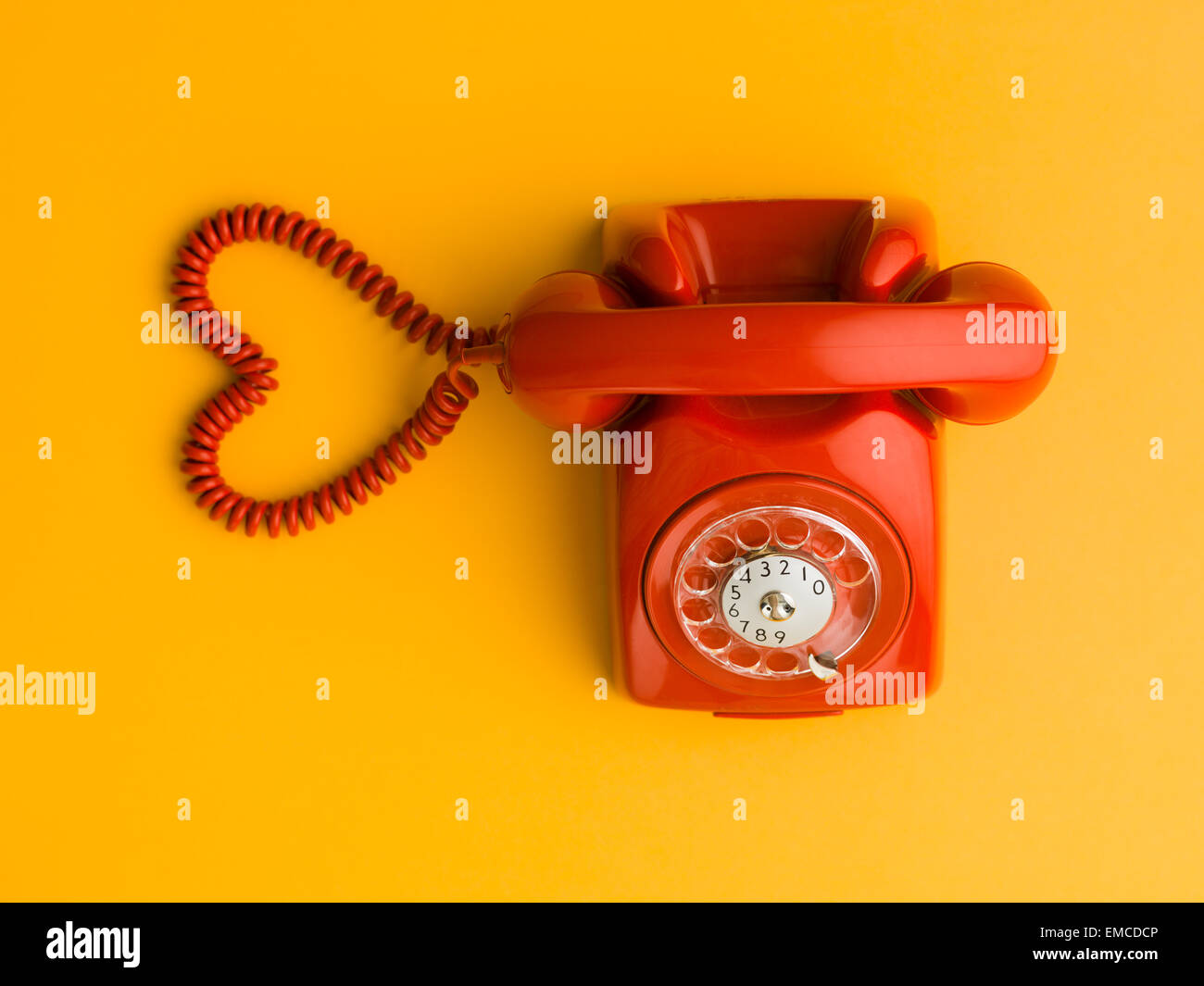 upper view of red phone with heart shape made out of its cable, on ...