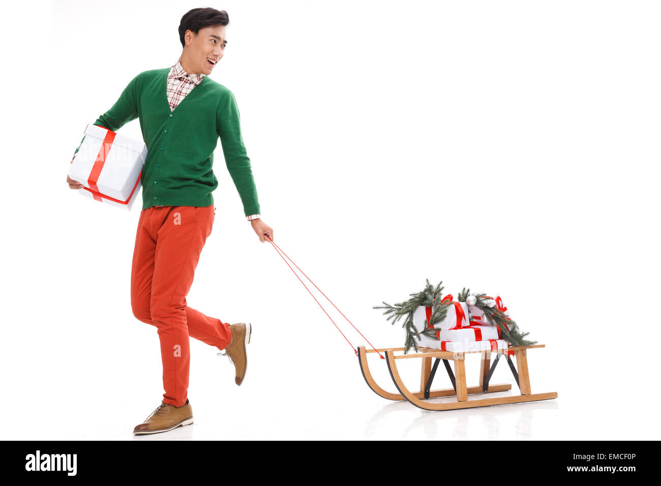 The young man pull a sled with a Christmas gift Stock Photo - Alamy