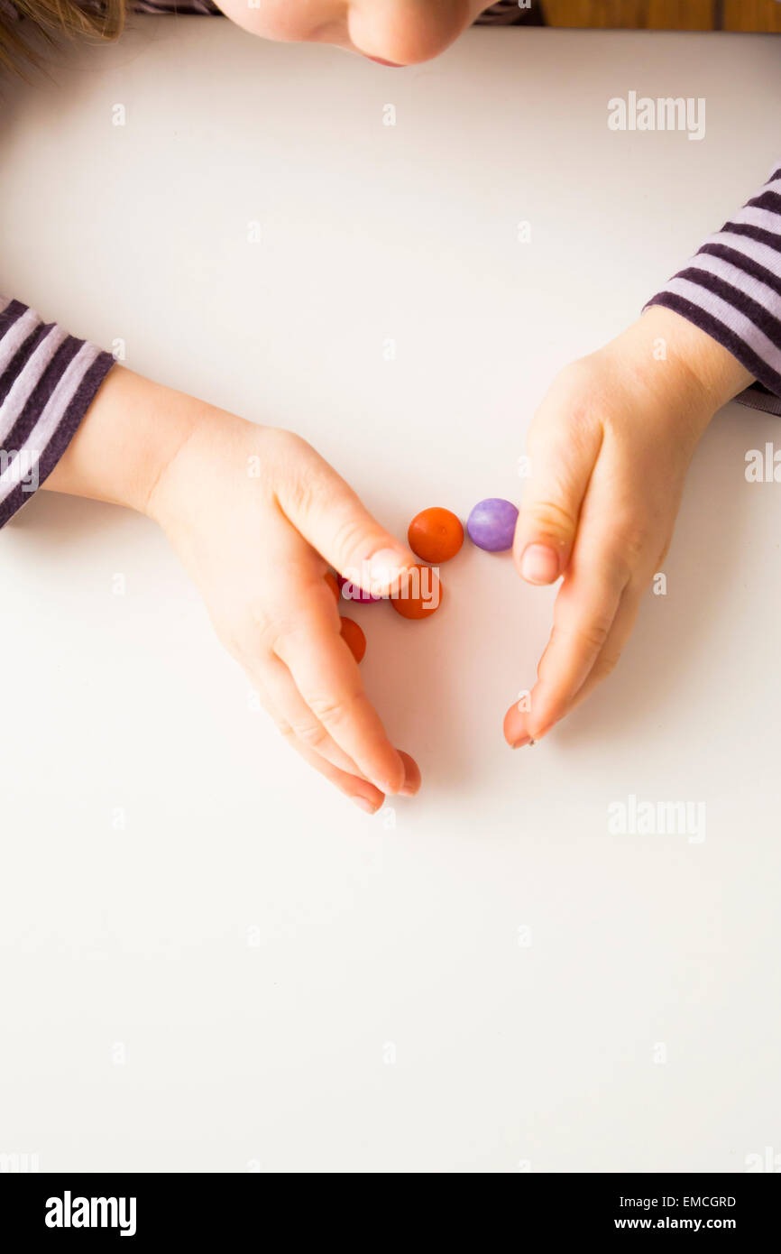 Little girl playing with chocolate buttons Stock Photo - Alamy
