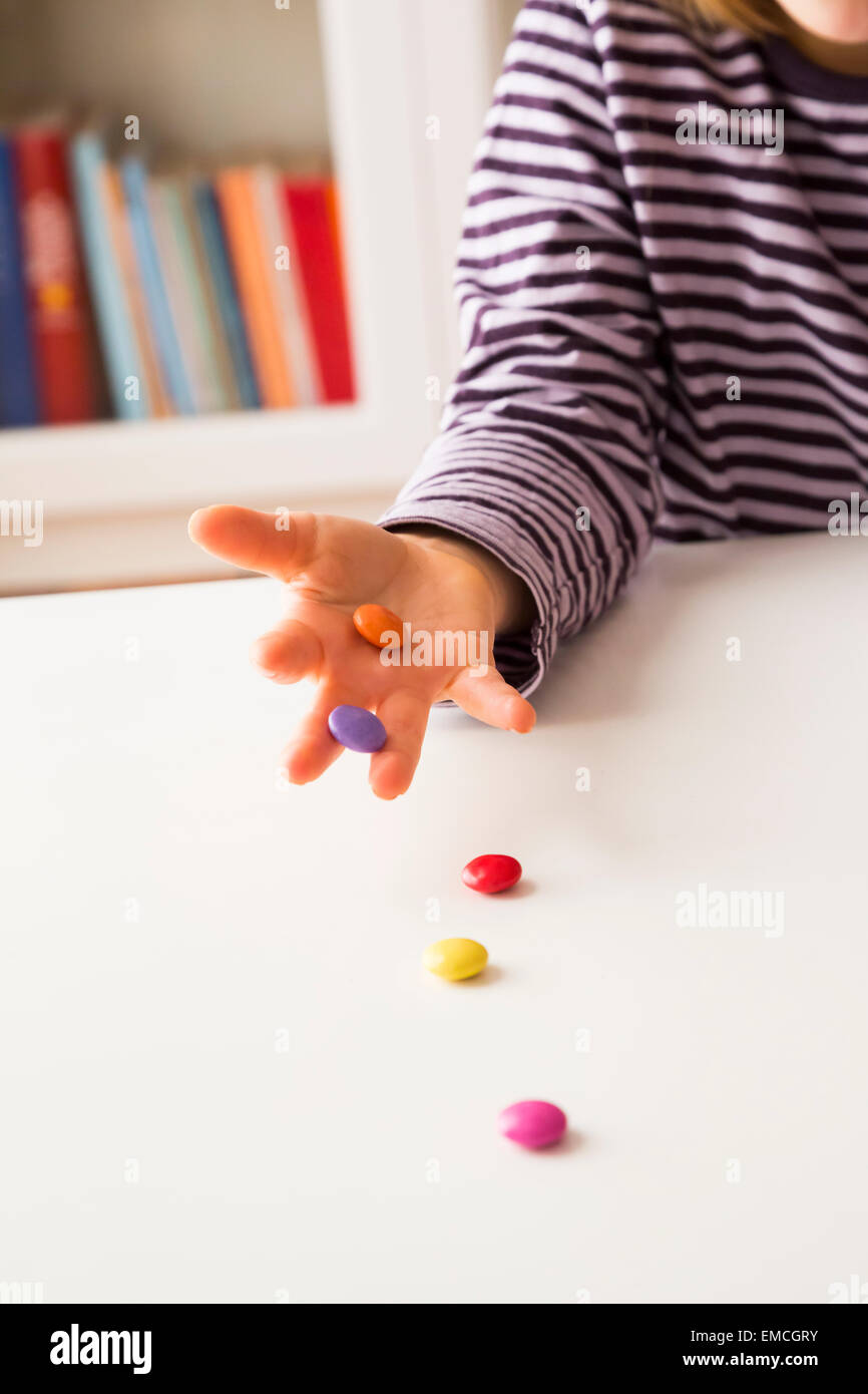 Little girl playing with chocolate buttons Stock Photo - Alamy