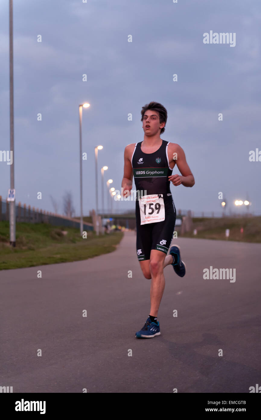 Teenager triathele running as part of a duathlon race with floodlights ...