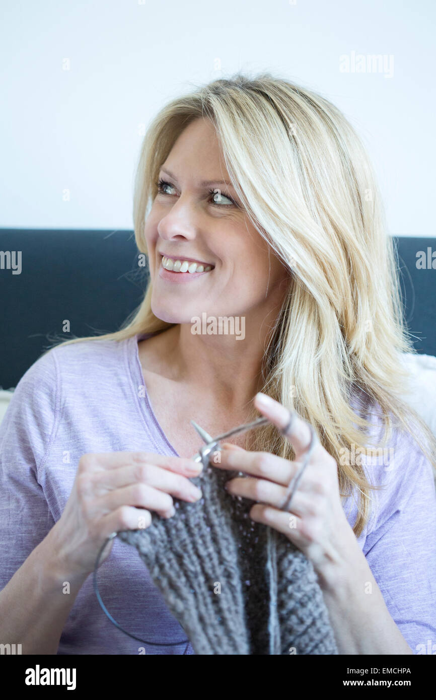 Portrait of blond woman knitting Stock Photo - Alamy