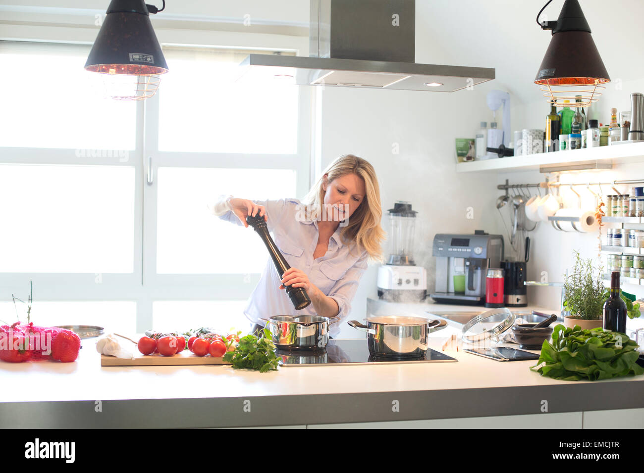 Woman cooking in kitchen using pepper grinder Stock Photo - Alamy