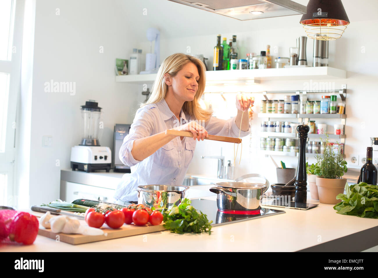 Smiling woman cooking spaghetti in kitchen Stock Photo - Alamy