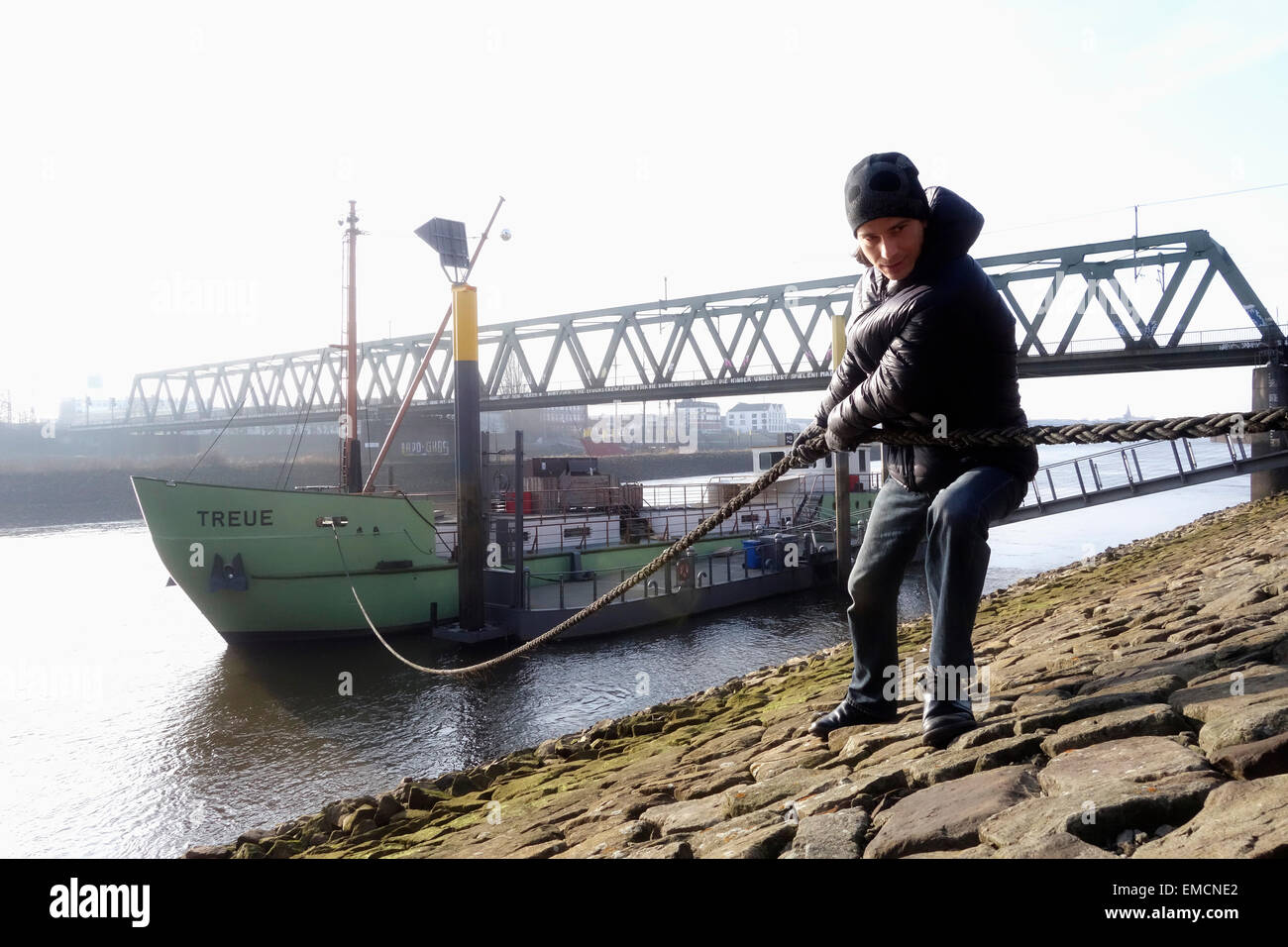 Germany, Bremerhaven, man pulling rope of freight ship Stock Photo - Alamy